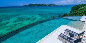 Piscina infinita com vista para o oceano e uma ilha ao longe.