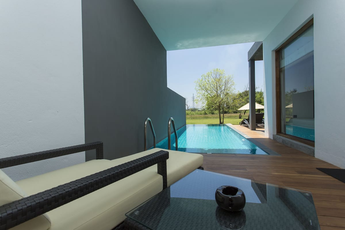Uma área moderna de piscina ao ar livre, com mesa de vidro e um banco acolchoado.