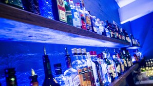 Um bar com prateleiras cheias de garrafas de bebidas alcoólicas.