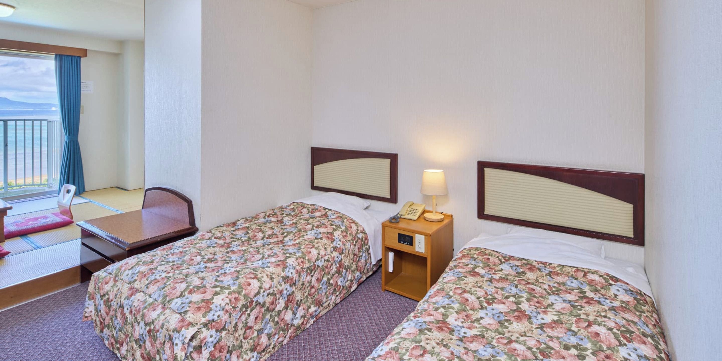 Quarto de hotel com duas camas, uma escrivaninha e uma cadeira.