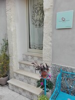 Entrada de um edifício com uma placa, degraus decorados e um vaso de planta.