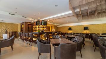 Um restaurante moderno com área de bar, assentos de couro e teto decorativo.