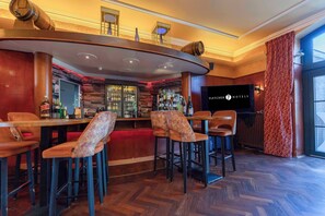 Uma área de bar com banquetas de madeira, um balcão e uma garrafa de bebida alcoólica.