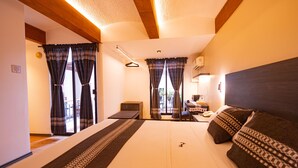 Quarto de hotel com uma cama grande, uma mesa com cadeira e vista pelas cortinas.
