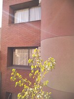 Um edifício com fachada de tijolos e uma janela com cortinas.