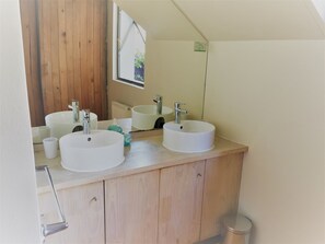 Casa de banho com duas pias, espelho e armários de madeira.