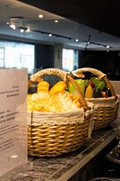 Duas cestas de vime repletas de frutas e legumes sobre um balcão com um letreiro de menu.