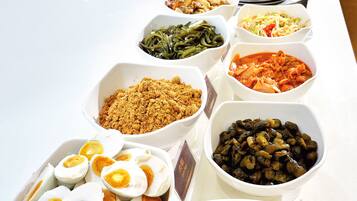 Uma mesa de buffet com diversos alimentos, incluindo ovos, vegetais e molhos.