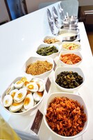 Uma mesa de buffet com diversos alimentos, incluindo ovos, vegetais e molhos.