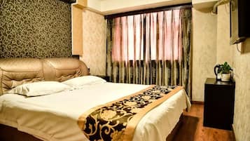 Quarto de hotel com cama, cortinas, uma mesinha com uma planta e parede estampada.