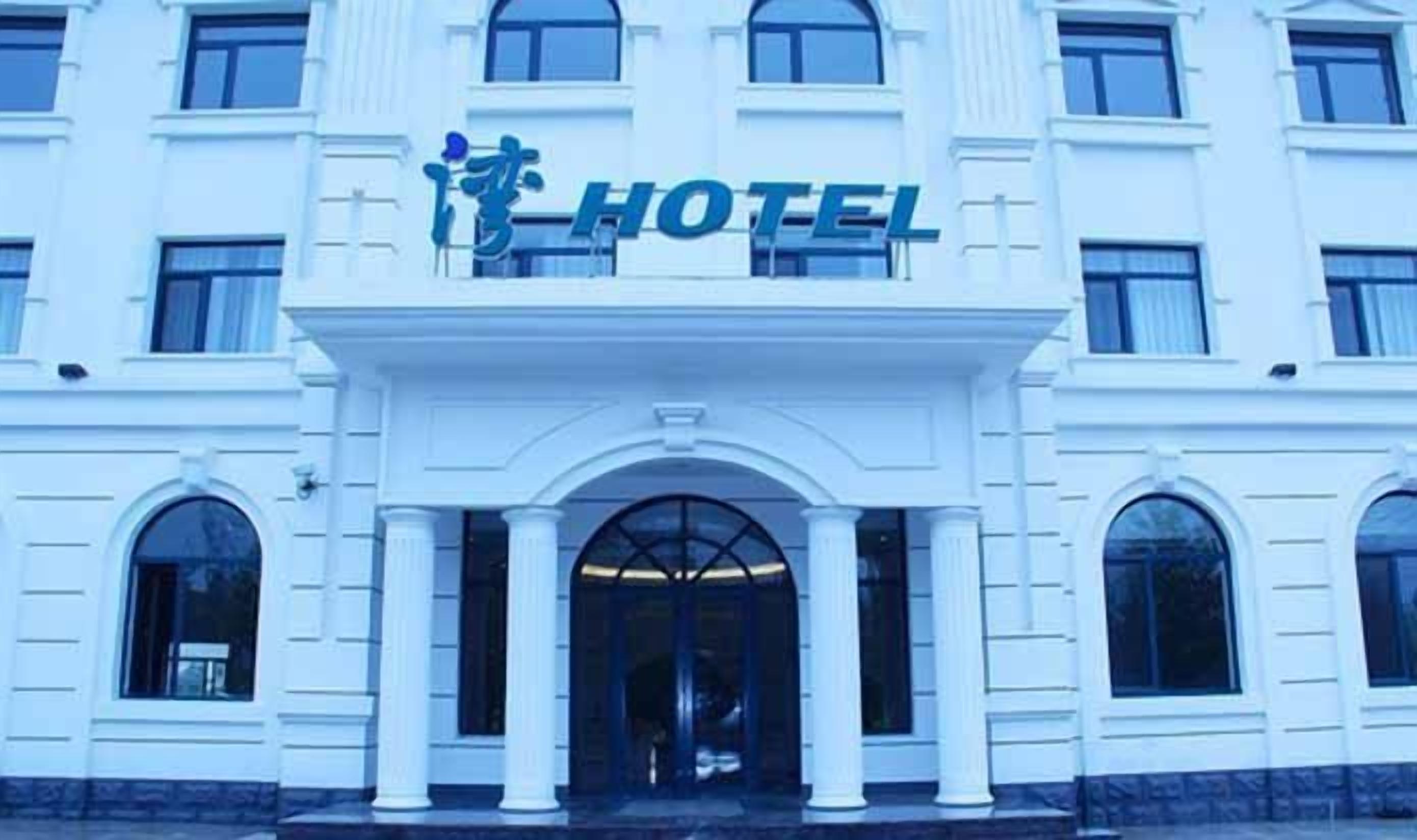 Entrada de hotel com uma placa que diz 'HOTEL' em inglês e outro idioma.