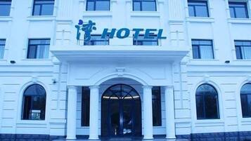 Entrada de hotel com uma placa que diz 'HOTEL' em inglês e outro idioma.
