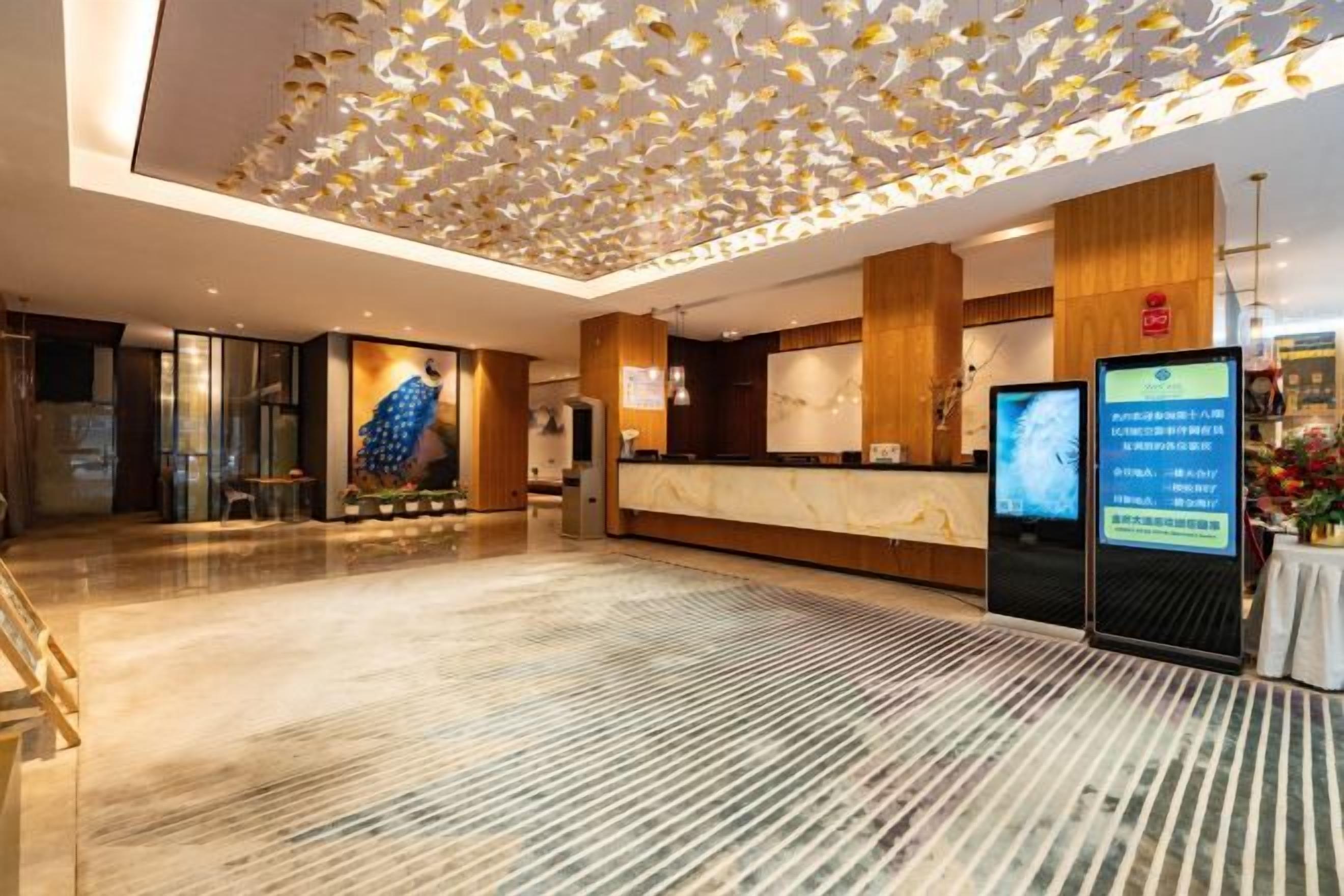 Uma área de recepção de hotel com design moderno, balcão de atendimento e displays de informação digital.