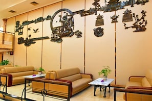 Um saguão de hotel com decoração tradicional asiática, incluindo obras de arte nas paredes e mobiliário.