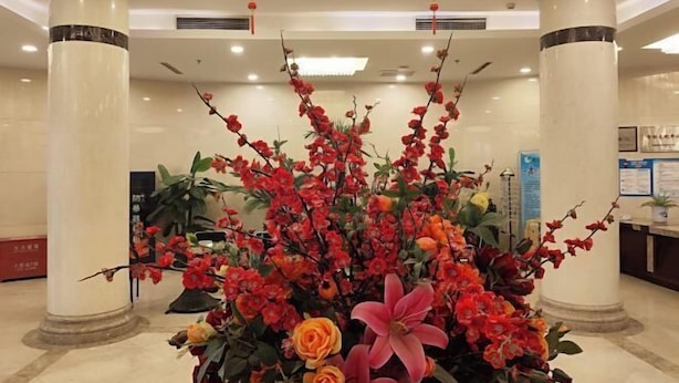 Um saguão com grandes colunas brancas, um arranjo floral e um balcão de recepção.