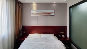 Quarto de hotel com uma cama grande, cabeceira de madeira, mesa de cabeceira com telefone e um quadro na parede.