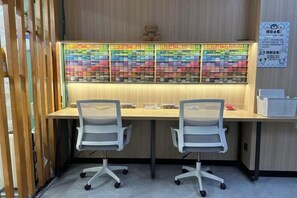 Um espaço de trabalho com duas cadeiras de escritório, uma mesa e um monitor grande fixado na parede.