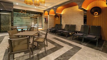 Um hall com piscina, área de estar e balcão de recepção.