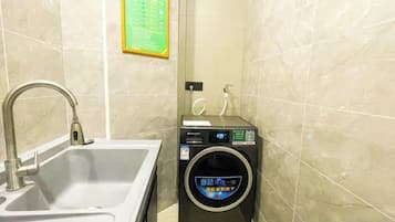 Casa de banho com lavatório, máquina de lavar e espelho fixado na parede.