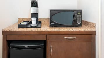 Uma cozinha compacta equipada com cafeteira, micro-ondas e máquina de lavar louça.