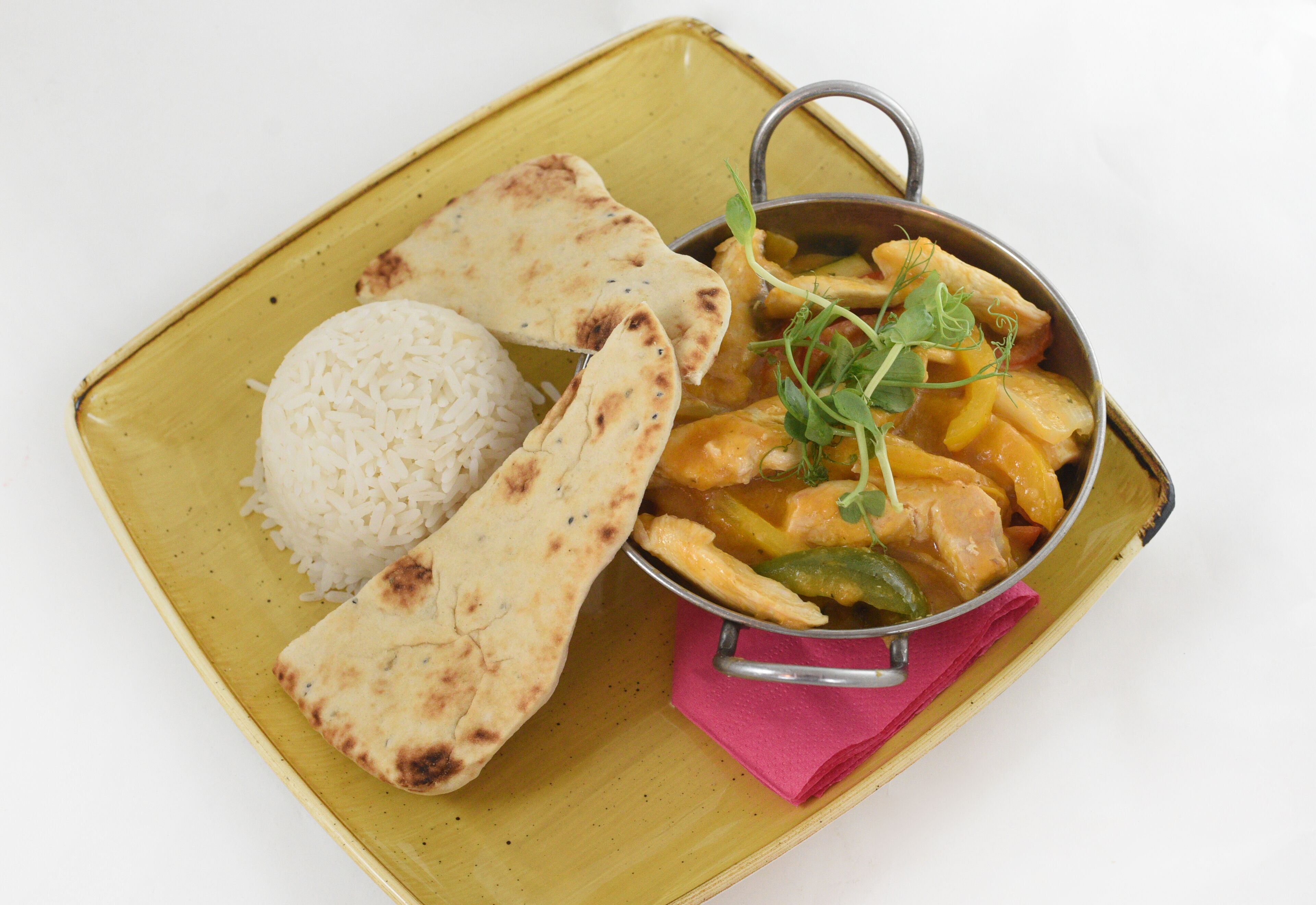 Um prato com arroz, pão naan e um curry.