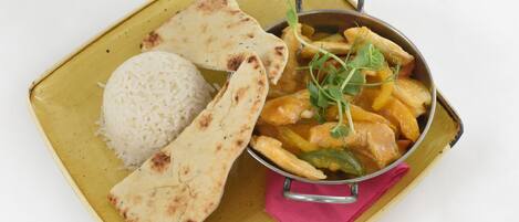 Um prato com arroz, pão naan e um curry.
