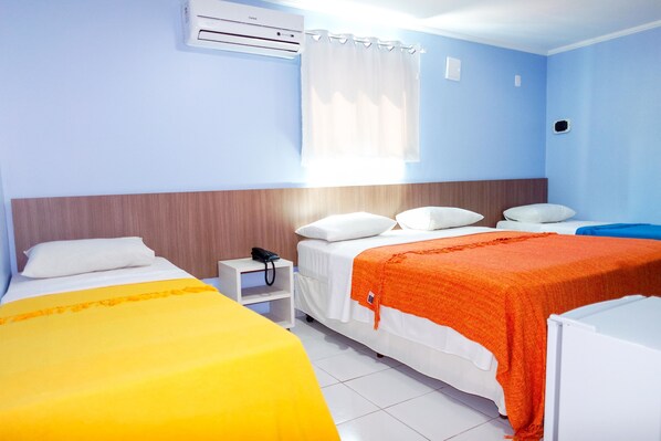 Quarto de hotel com duas camas, uma mesa de cabeceira com telefone e um aparelho de ar condicionado.