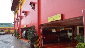 Edifício vermelho com placa amarela indicando altura livre de 2,10m.