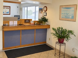 Bancada de recepção com indicação do horário de check-out, um relógio e um quadro na parede.