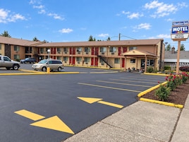 Um motel com estacionamento, vagas demarcadas e um edifício com vários andares e varandas.