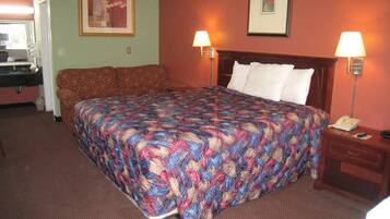 Quarto de hotel com uma cama grande, duas luminárias de cabeceira, mesa de cabeceira com telefone e quadro na parede.