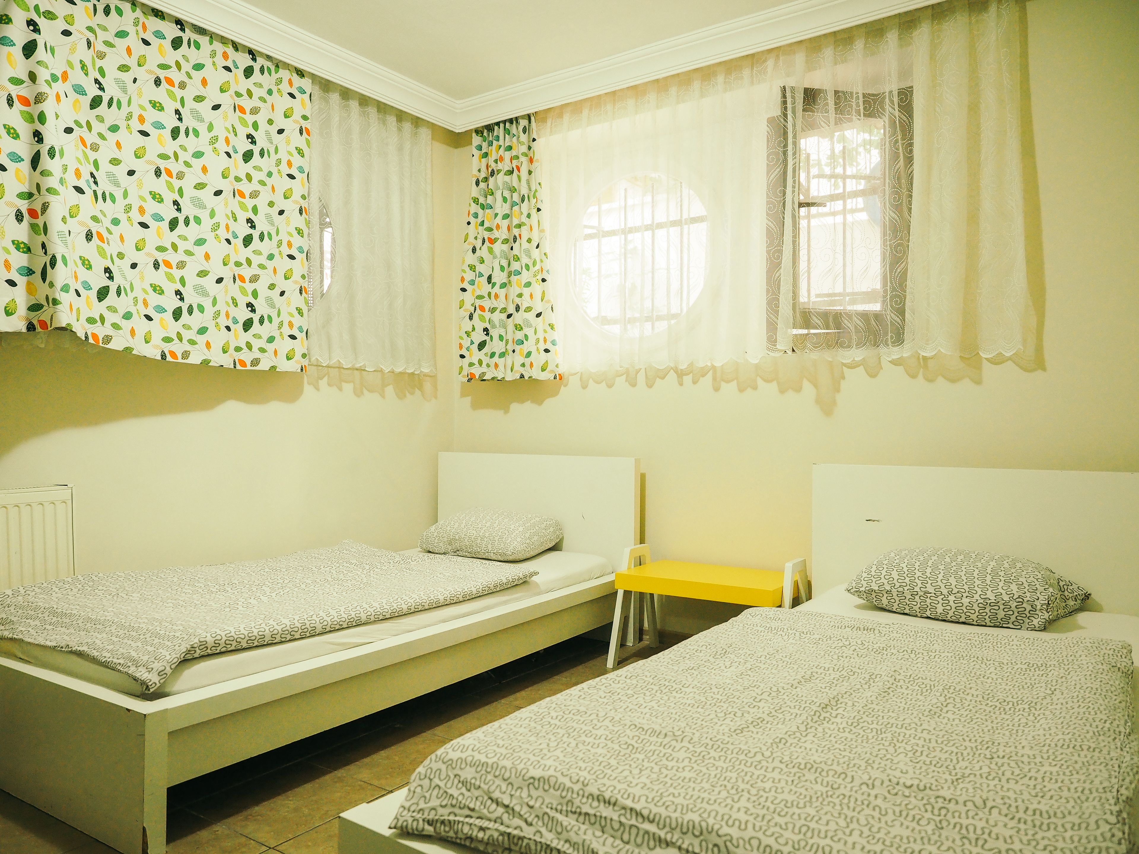 Quarto com duas camas de solteiro, uma mesa pequena e um radiador.
