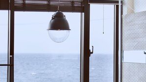 Uma casa de banho moderna com uma banheira grande, uma janela emoldurada em madeira e vista para o oceano.