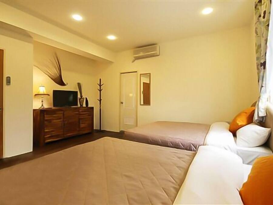 Quarto de hotel com duas camas, uma cômoda, uma televisão e um espelho.