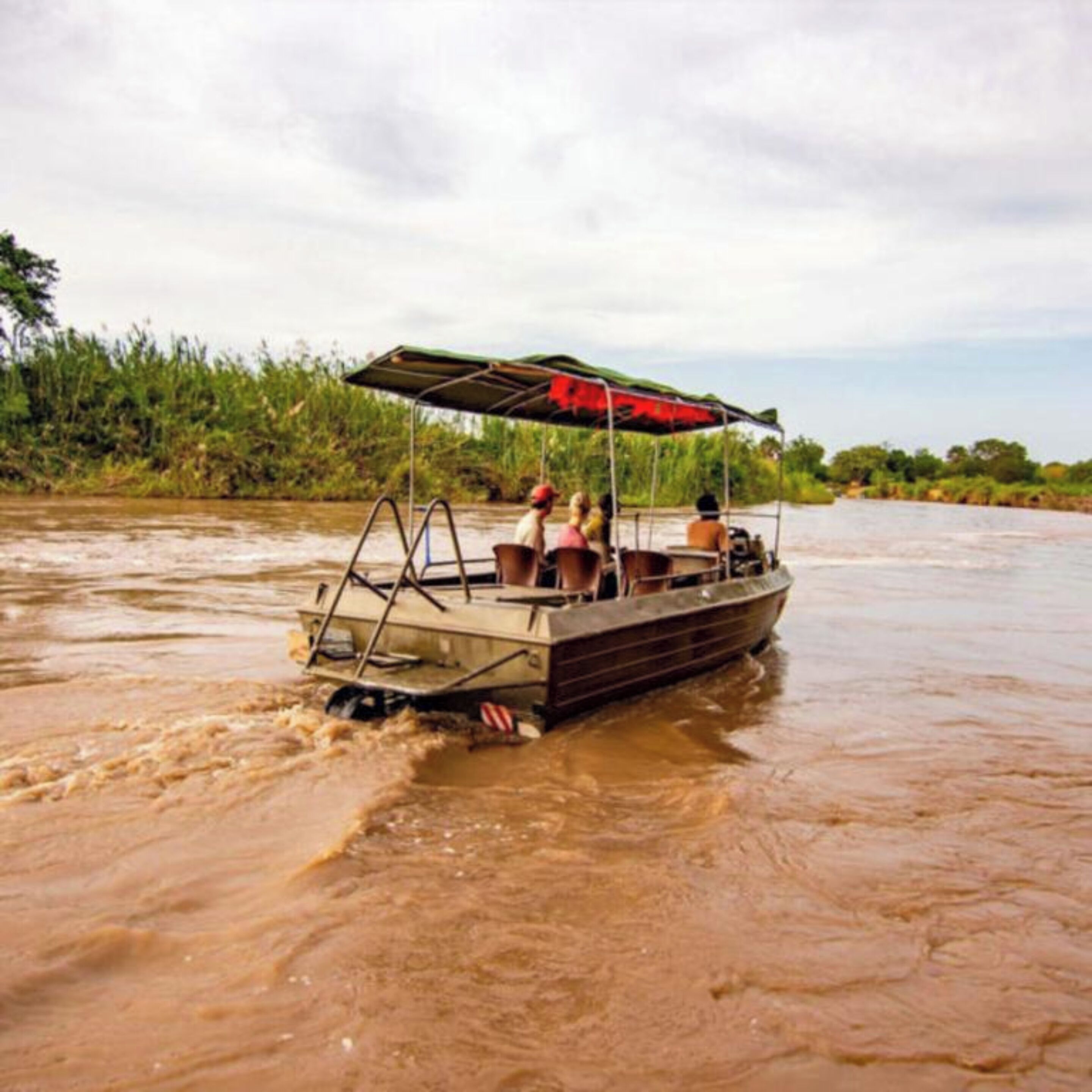 Um barco com toldo e passageiros em um rio.