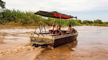 Um barco com toldo e passageiros em um rio.