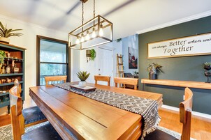 Uma área de refeições com uma mesa de madeira, bancos e um candelabro. Há um letreiro na parede que diz "fica sempre melhor quando estamos juntos.".