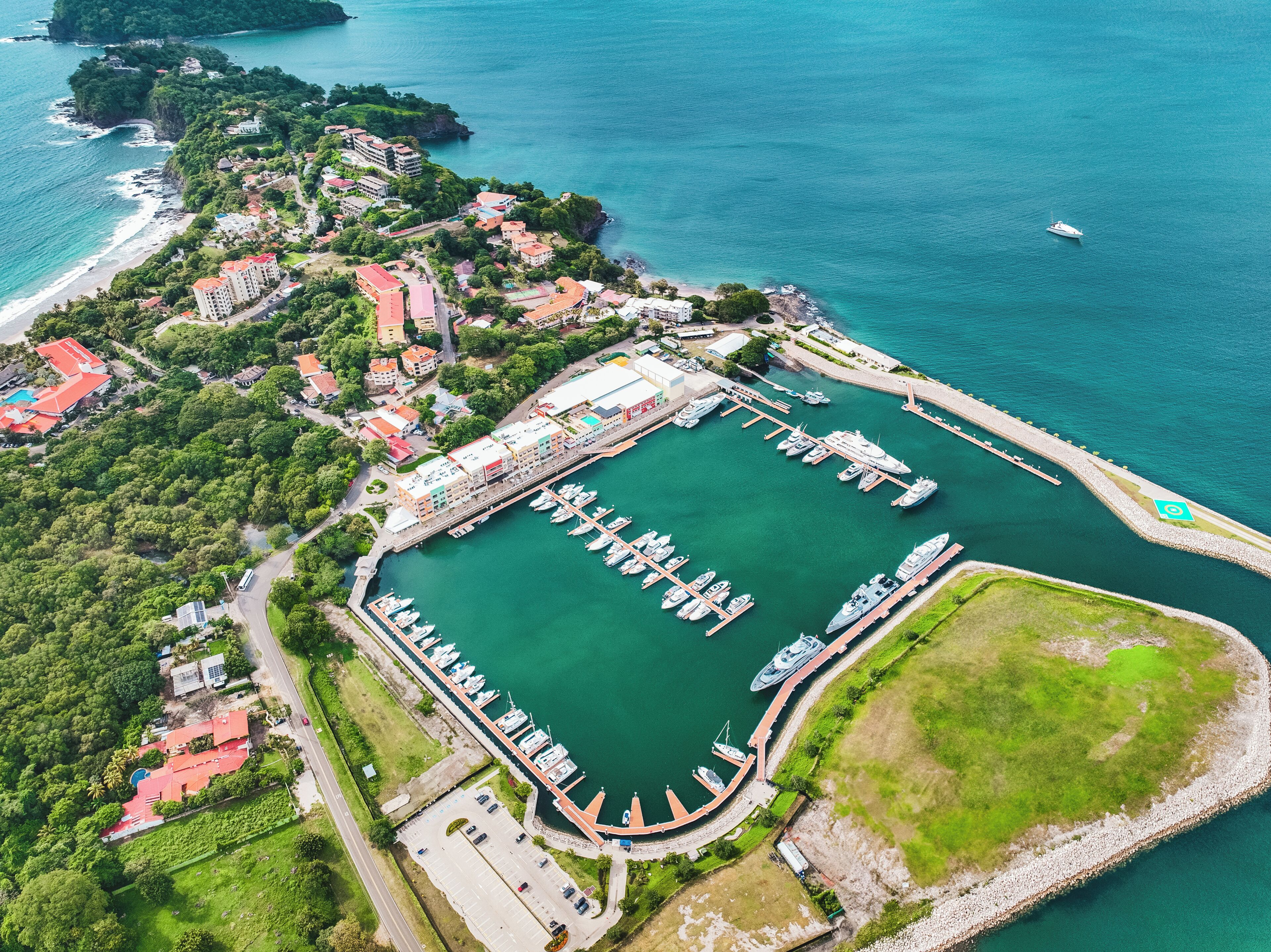 Vista aérea de uma marina com barcos atracados, um cais e edifícios ao redor.