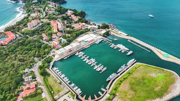 Vista aérea de uma marina com barcos atracados, um cais e edifícios ao redor.