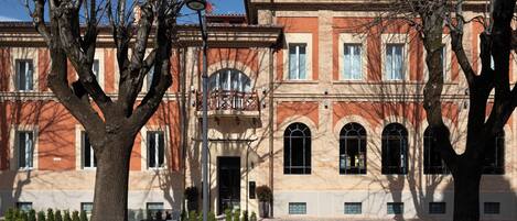 Um edifício com fachada simétrica, janelas em arco e varanda.