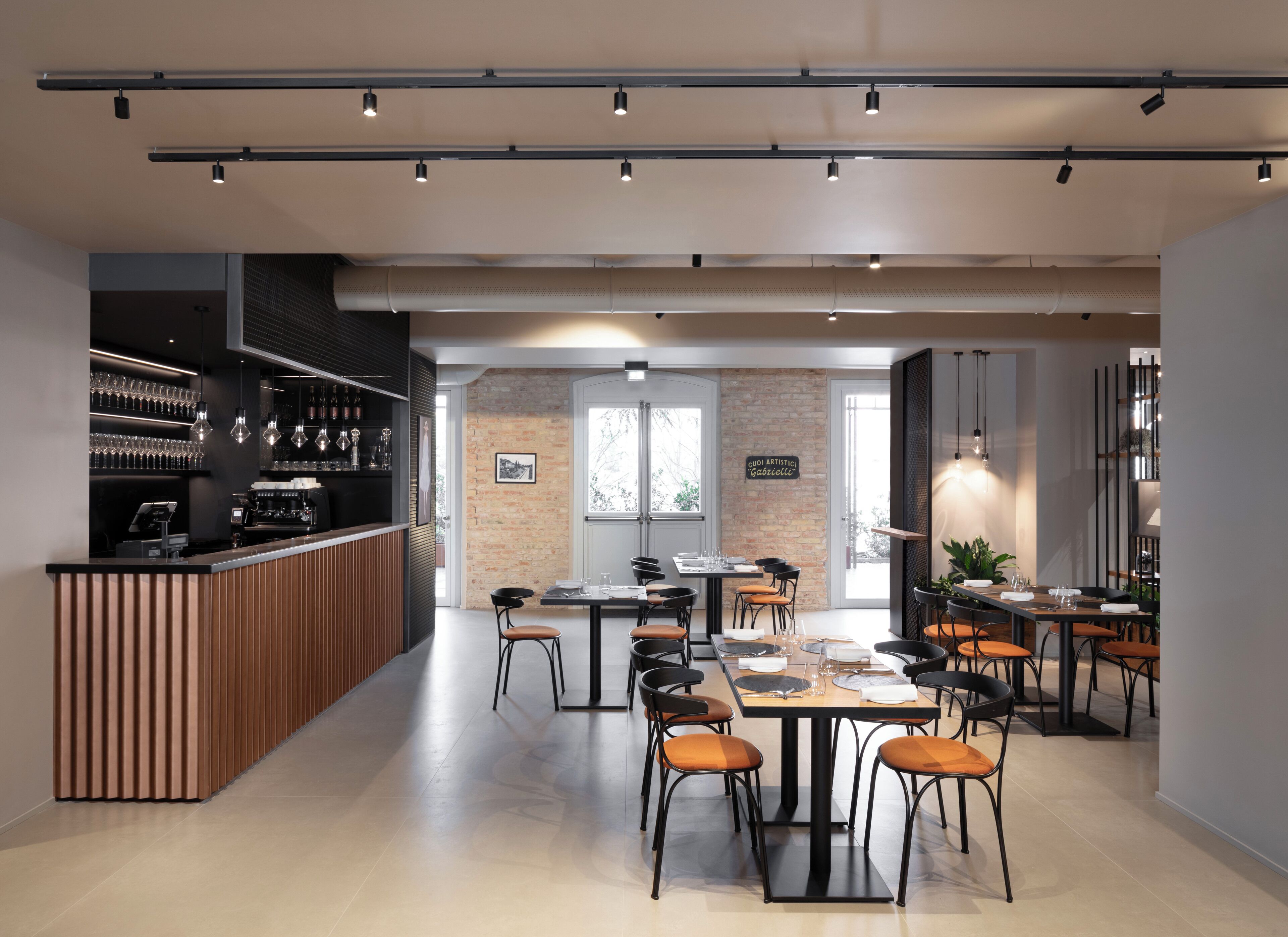 Restaurante moderno com área de bar, várias mesas e cadeiras.