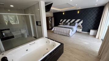 Quarto moderno com cama grande, banheiro separado com banheira e closet espaçoso.