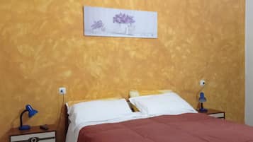 Quarto com cama, duas mesas de cabeceira, abajur, quadro na parede e guarda-roupa de madeira.