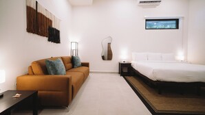 Quarto moderno com sofá, cama, mesa de cabeceira, luminária e obra de arte na parede.