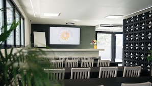 Uma sala de conferência com cadeiras brancas, uma mesa preta e uma tela exibindo "LOOKING GLASS SATURGY".