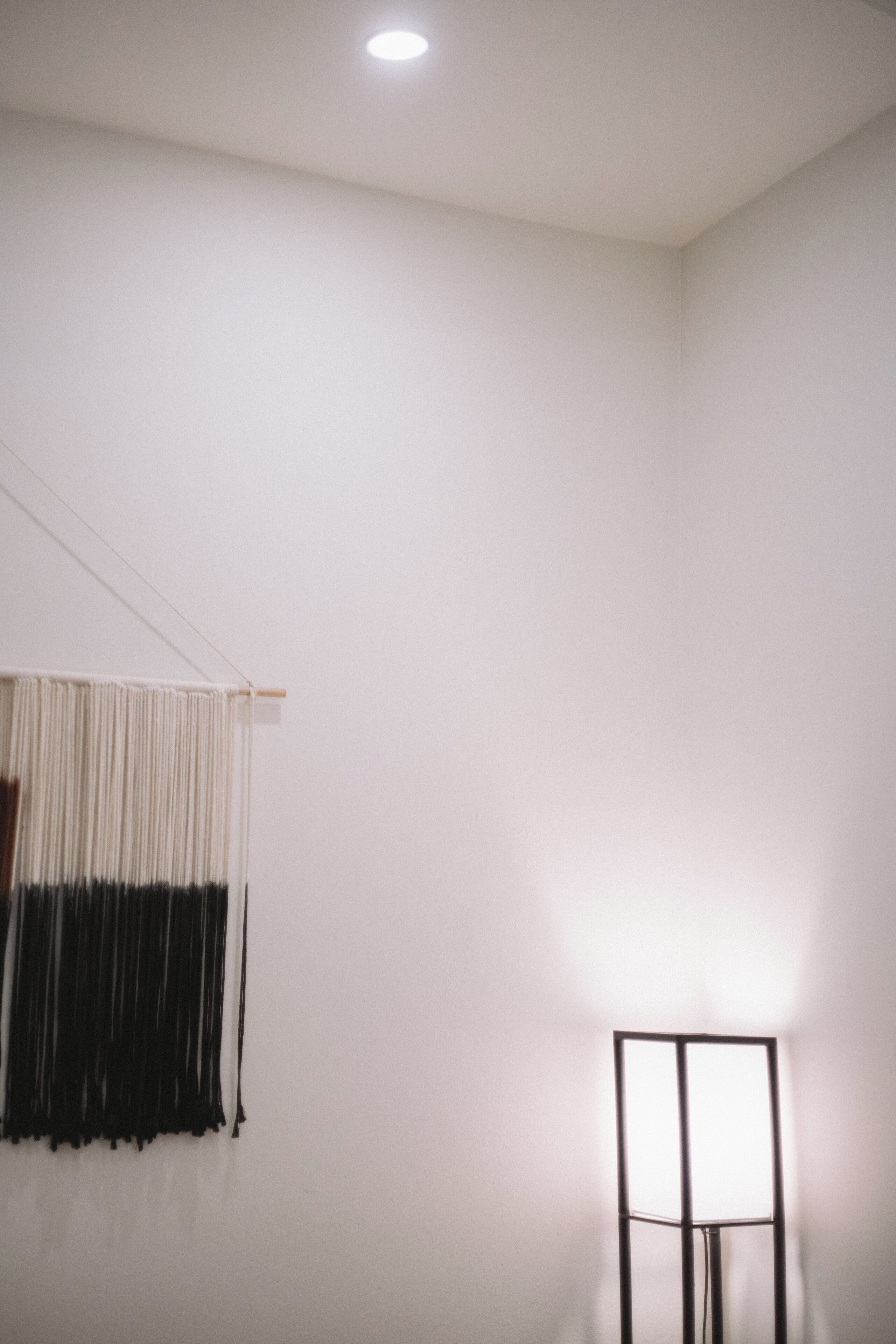 Quarto com parede branca, tecido pendurado e abajur.