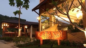 Placa do Katani Resort com entrada bem iluminada e área de estar coberta ao ar livre.