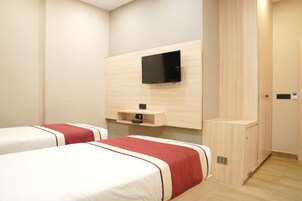 Quarto de hotel com duas camas, uma TV fixada na parede e um guarda-roupa de madeira.