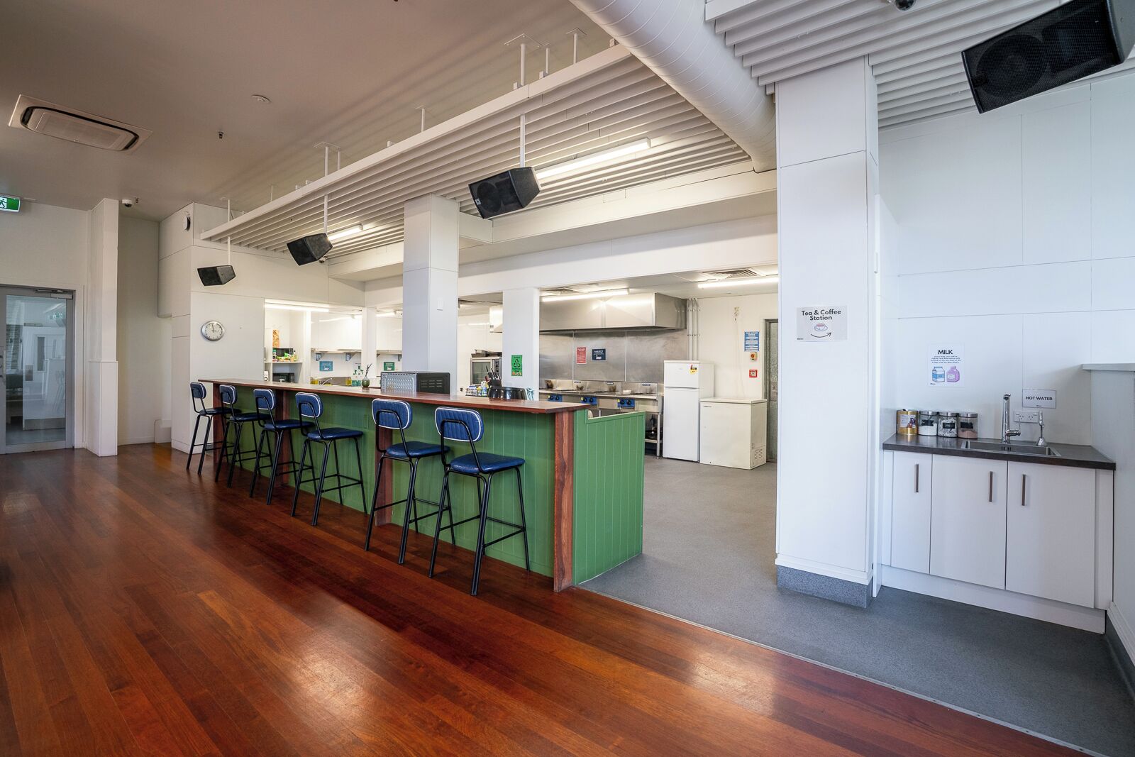 Cozinha moderna com área de bar, armários brancos e uma ilha verde com banquetas.