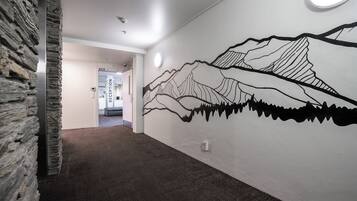 Um corredor com uma parede de pedra de um lado e um mural de montanhas do outro.